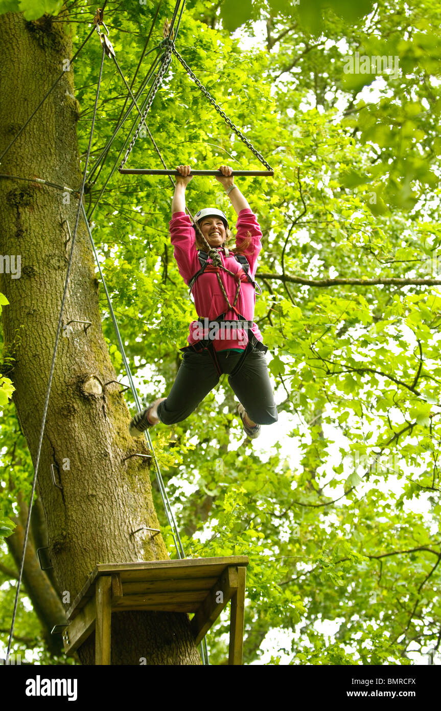Teenage girl on high ropes in the trees as part of a course organised ...