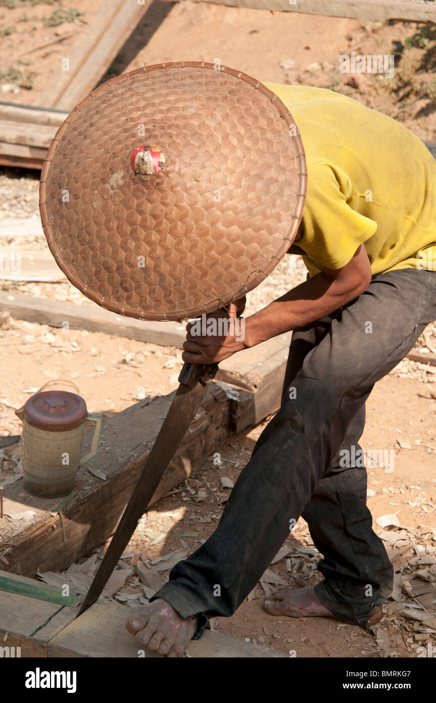 A Lao man sawing wood in a tribal village in Vong Xai province Northern ...