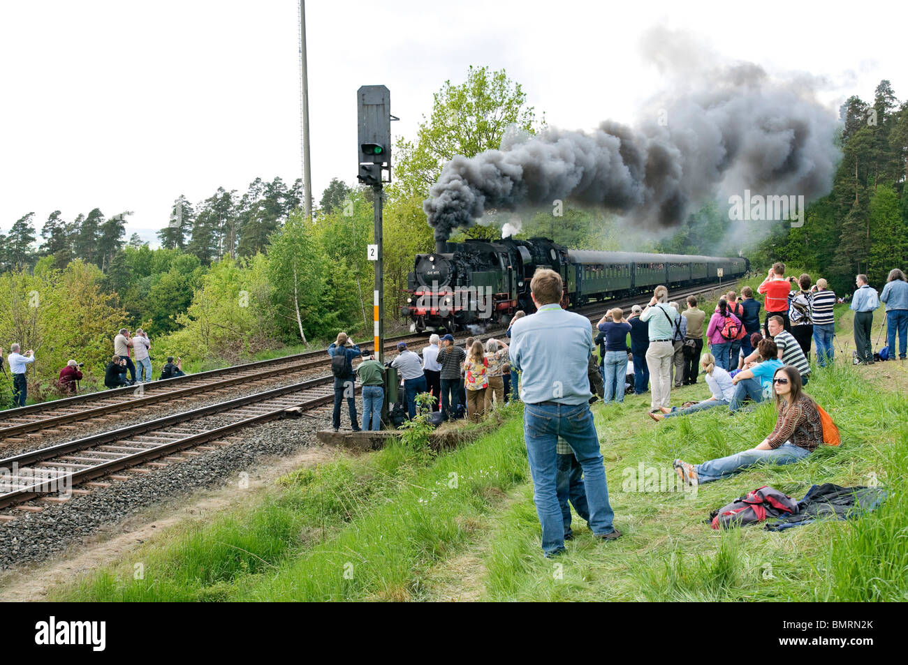 Railway enthusiasts watching steam train climbing incline near ...