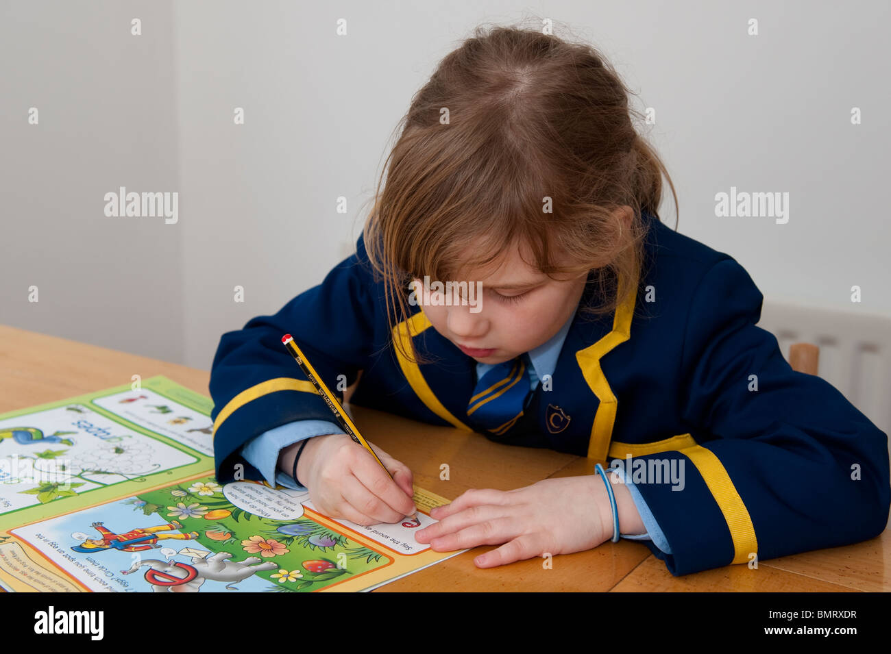 A young schoolgirl completes her homework assignment in writing ...