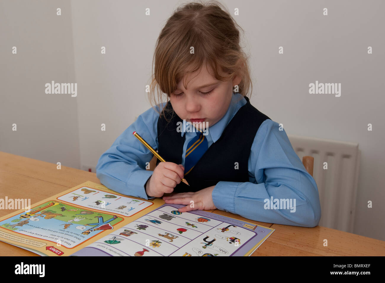 A young schoolgirl completes her homework assignment in writing ...