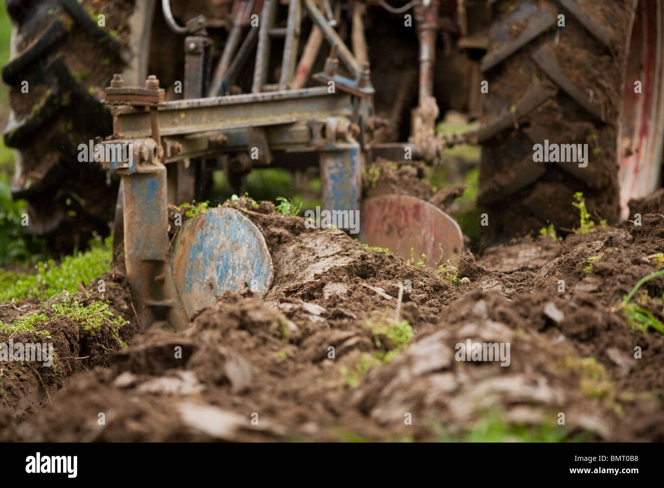Close up of the rear end of a tractor while plowing, some motion blur ...
