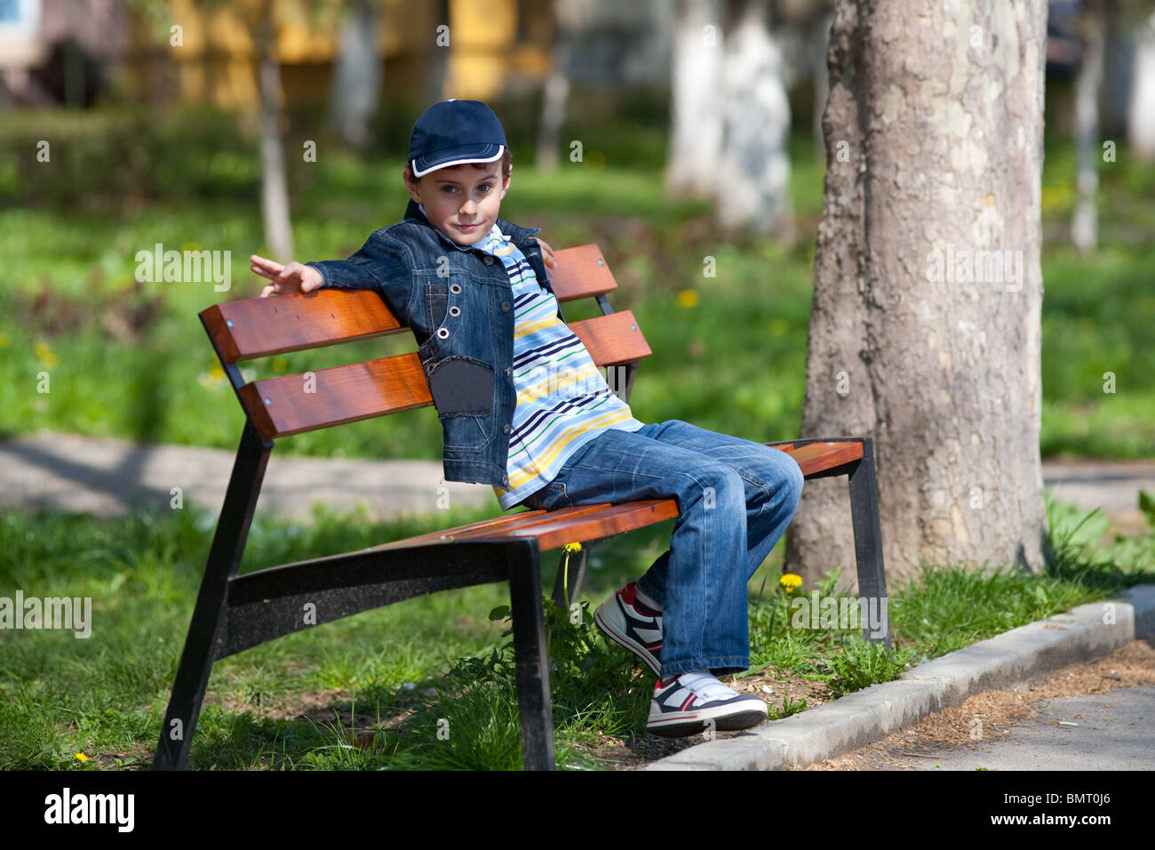 Little boy sitting on a bench in park Stock Photo - Alamy