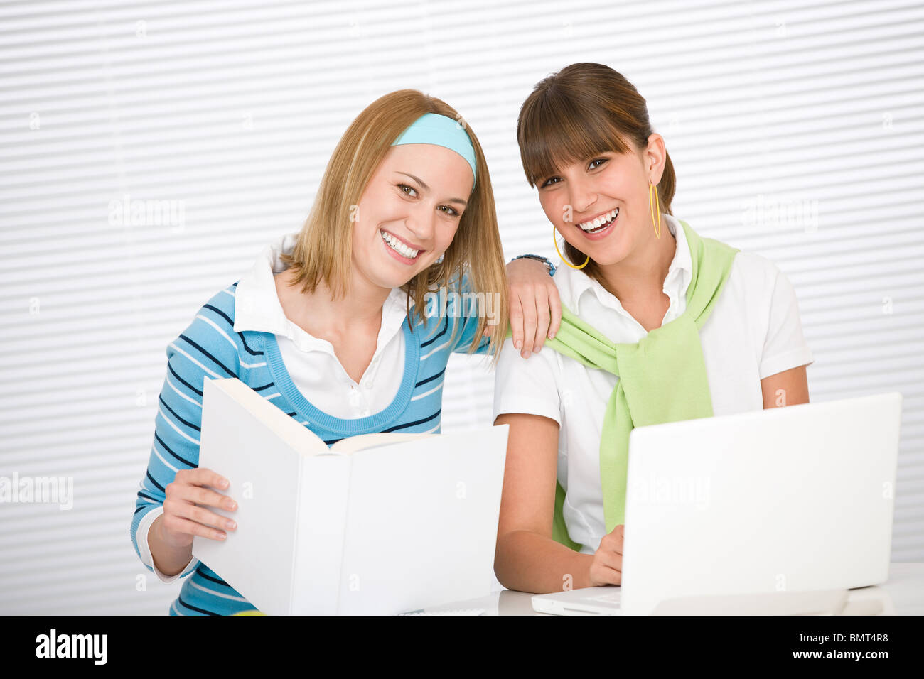 Student at home - two young woman study together with book and laptop ...