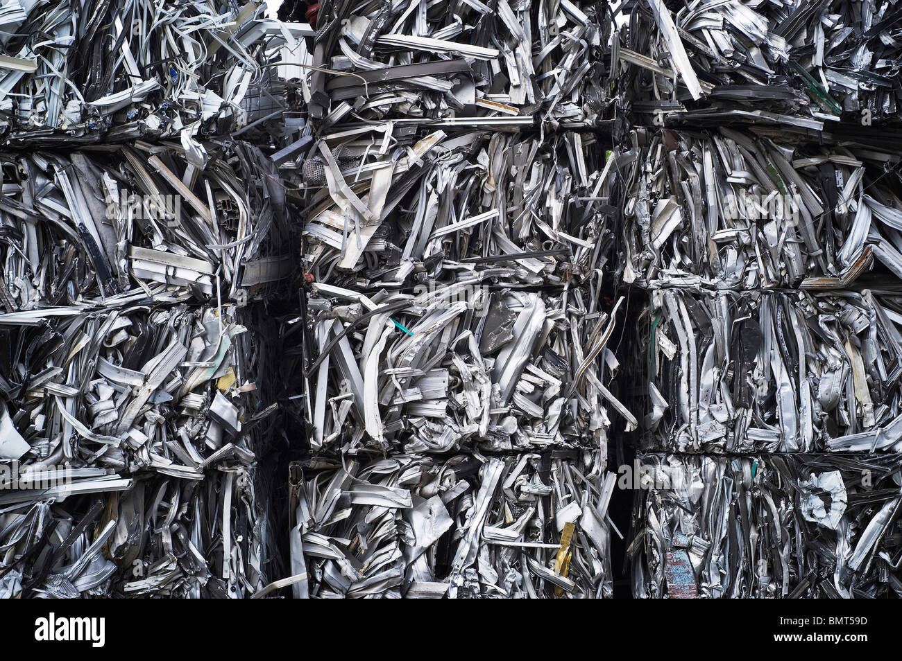 Scrap aluminum is crushed and baled, ready for transport and piled high ...