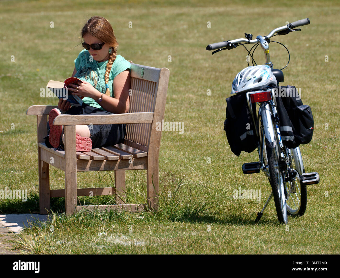woman reading book on park bench with bicycle, Devon, UK Stock Photo ...