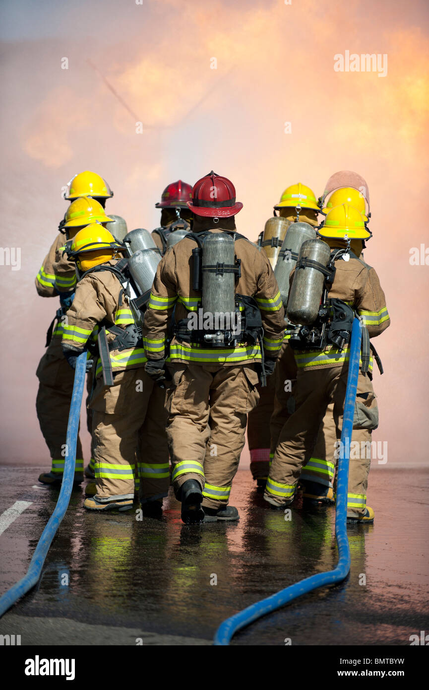 Directed by officers in red helmets, two teams of firefighters attack a ...
