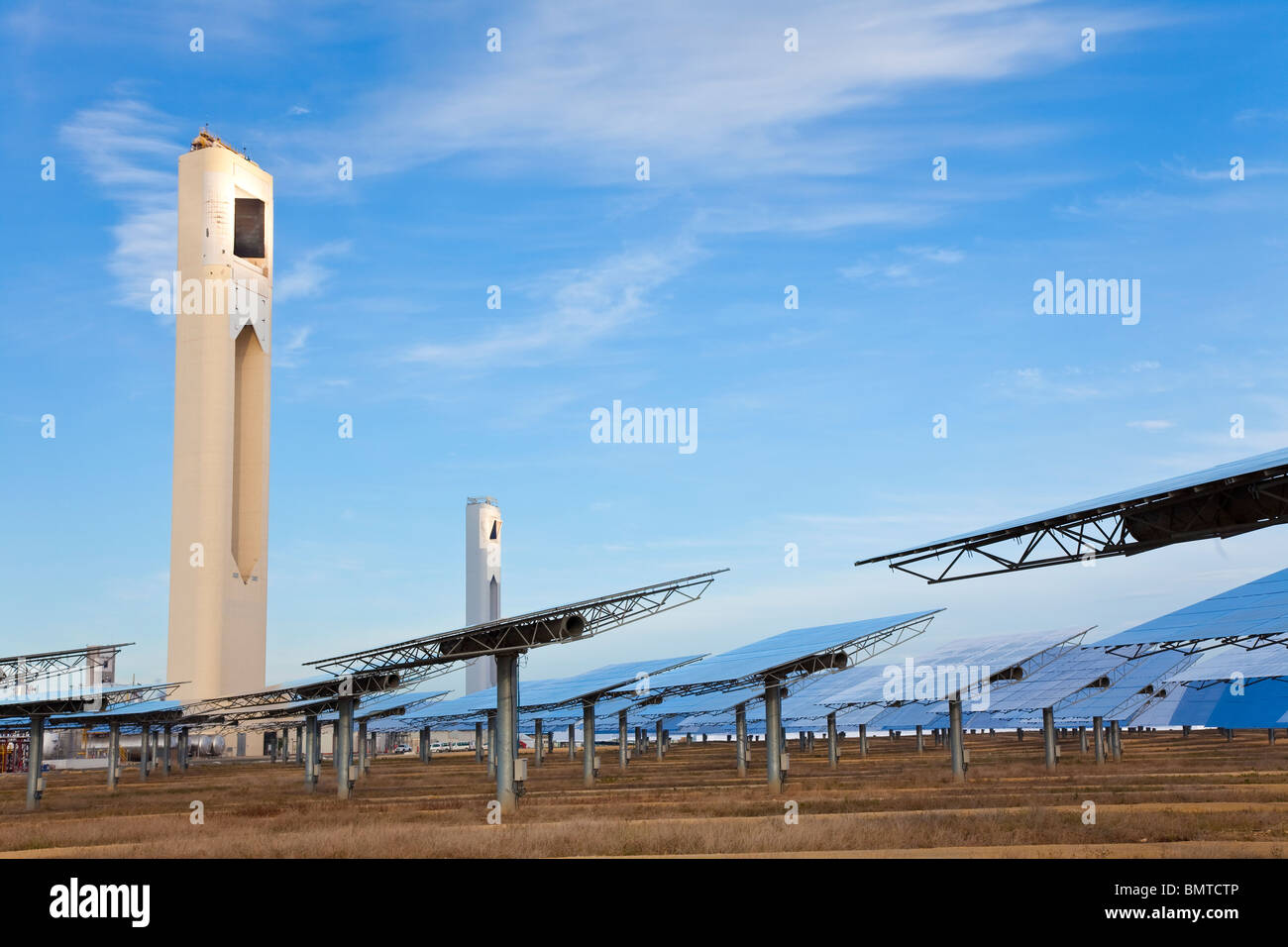 Two solar towers surrounded by mirror panels harnessing the sun's rays ...