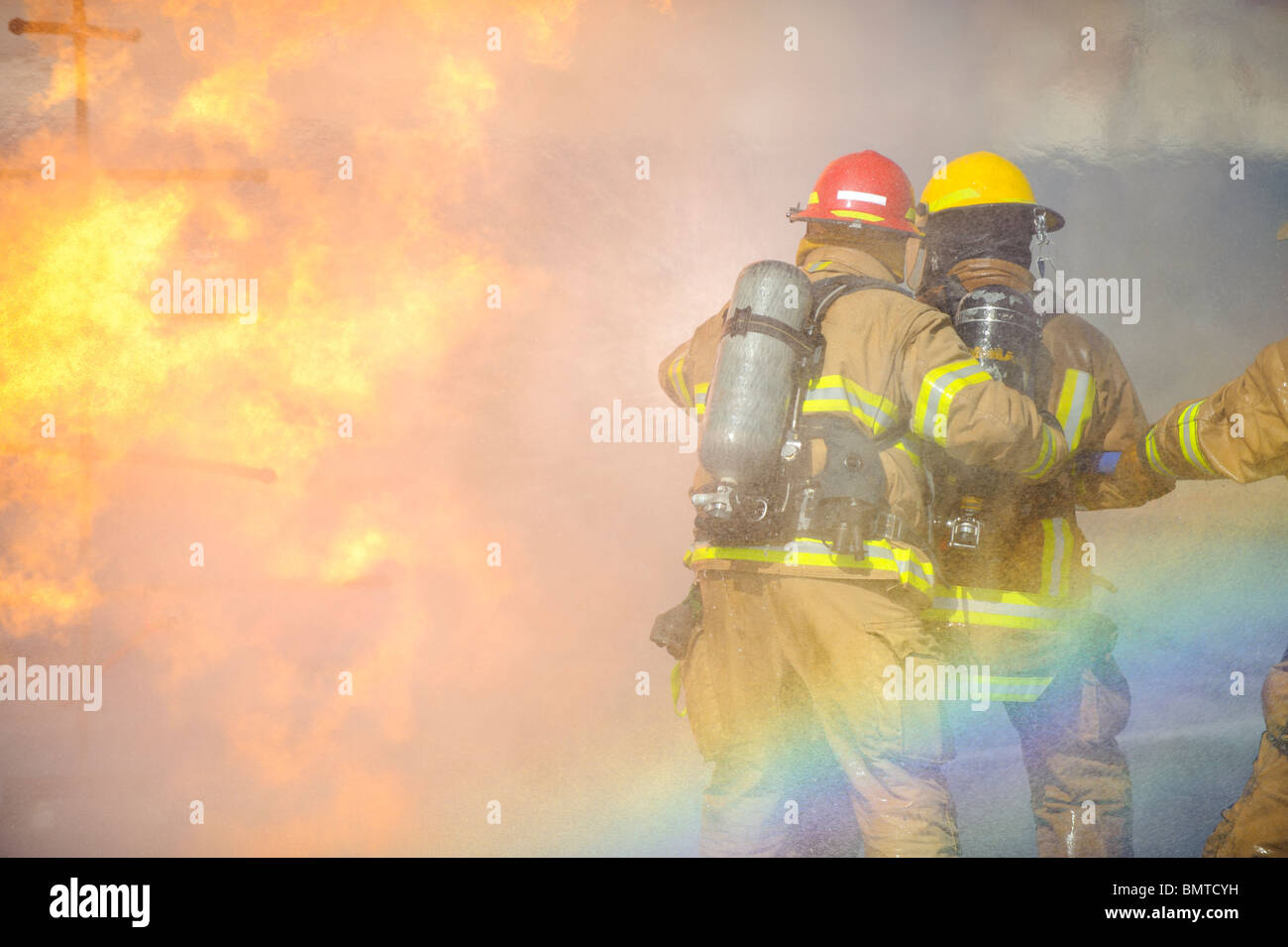 Directed by an officer in a red helmet, firefighters attack a propane ...