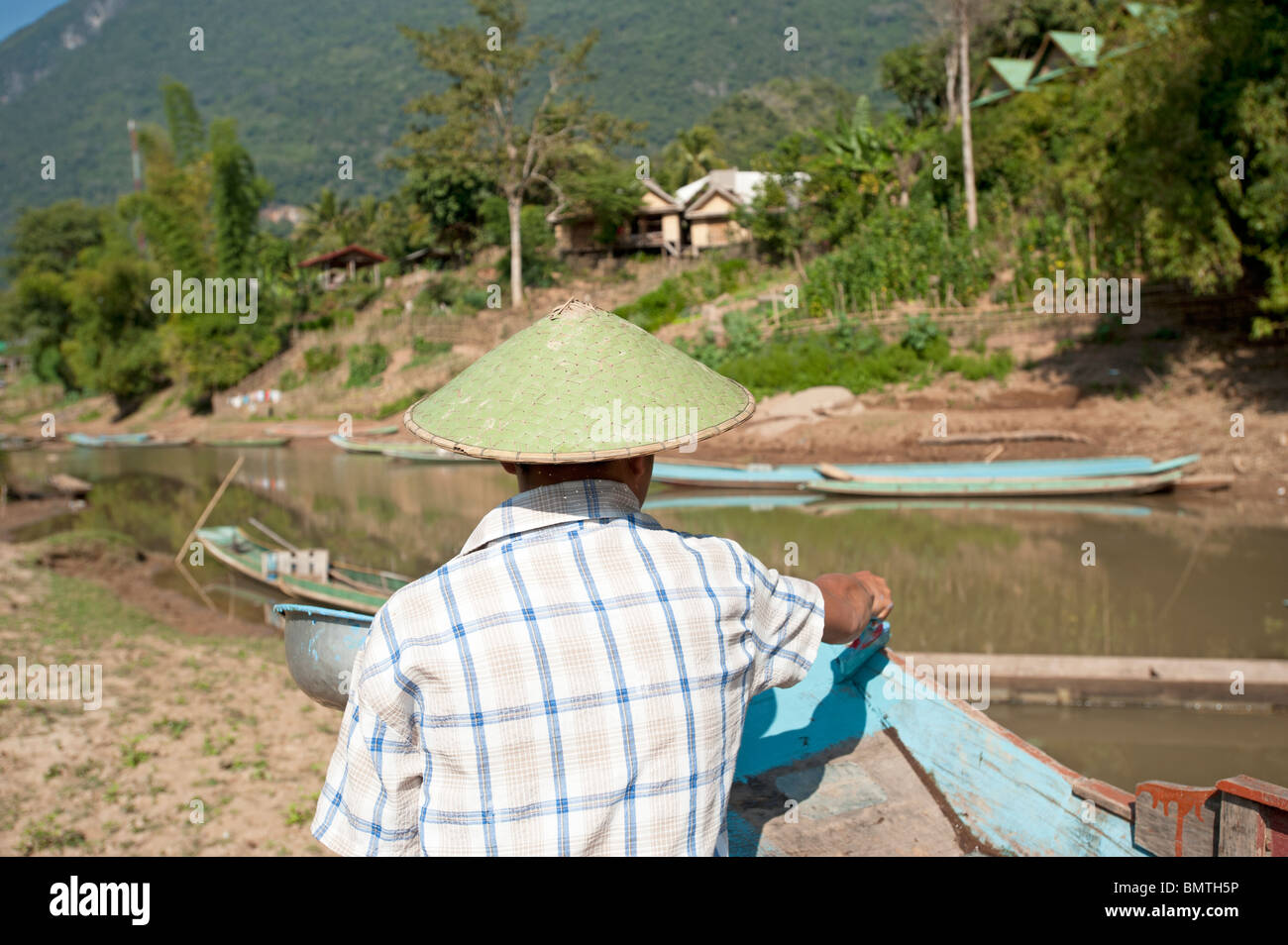 Lao man painting a canoe in Muang Ngoi Northern Laos Stock Photo - Alamy