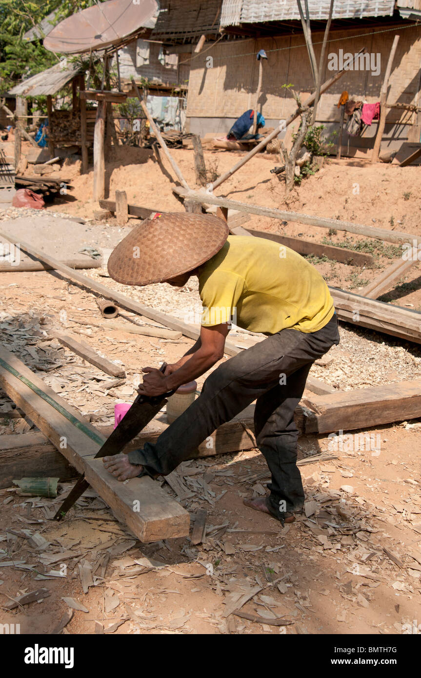 A Lao man sawing wood in a tribal village in Vong Xai province Northern ...