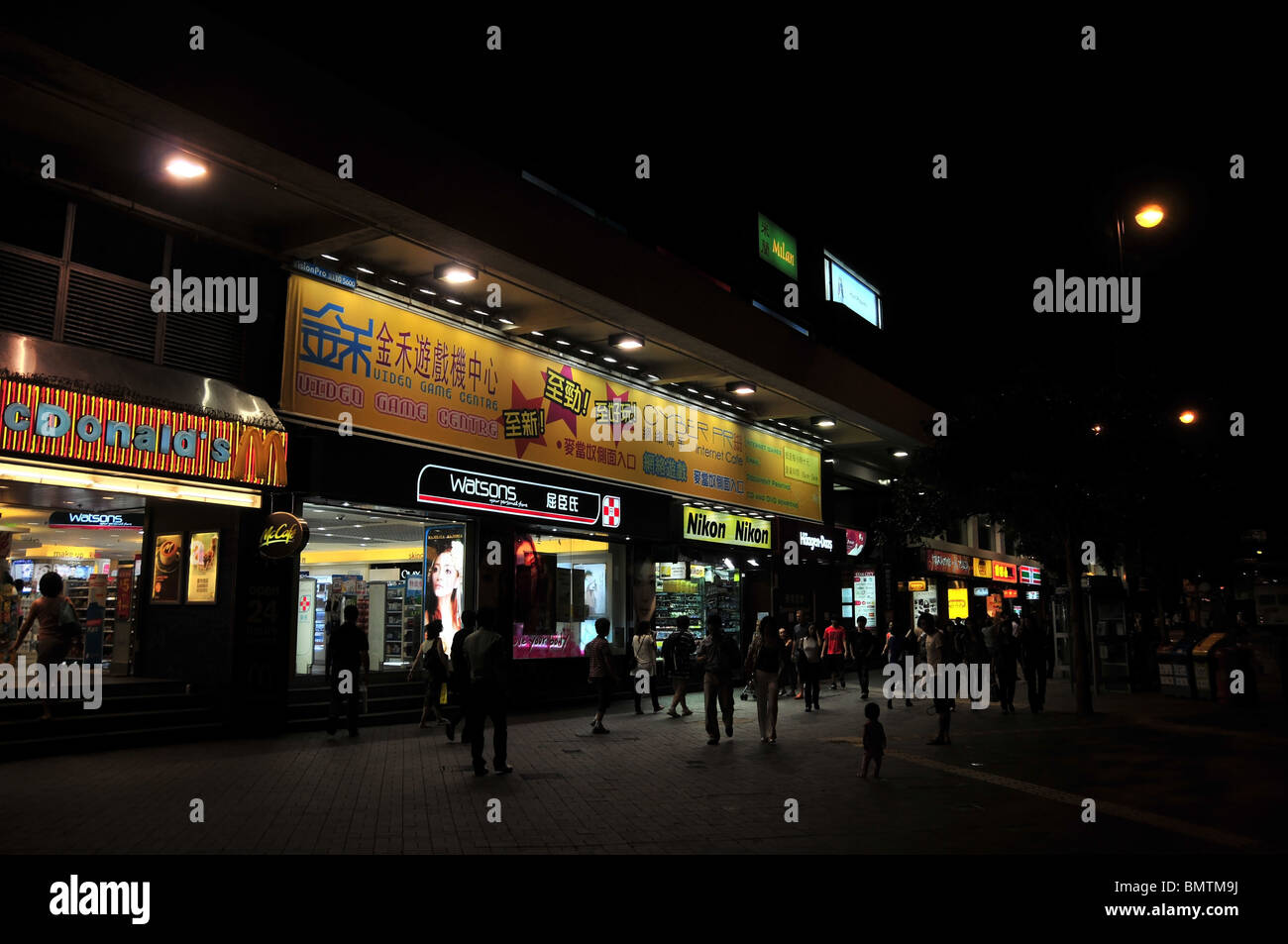 Oblique view of night-time neon chain stores and shoppers, Tsim Sha ...