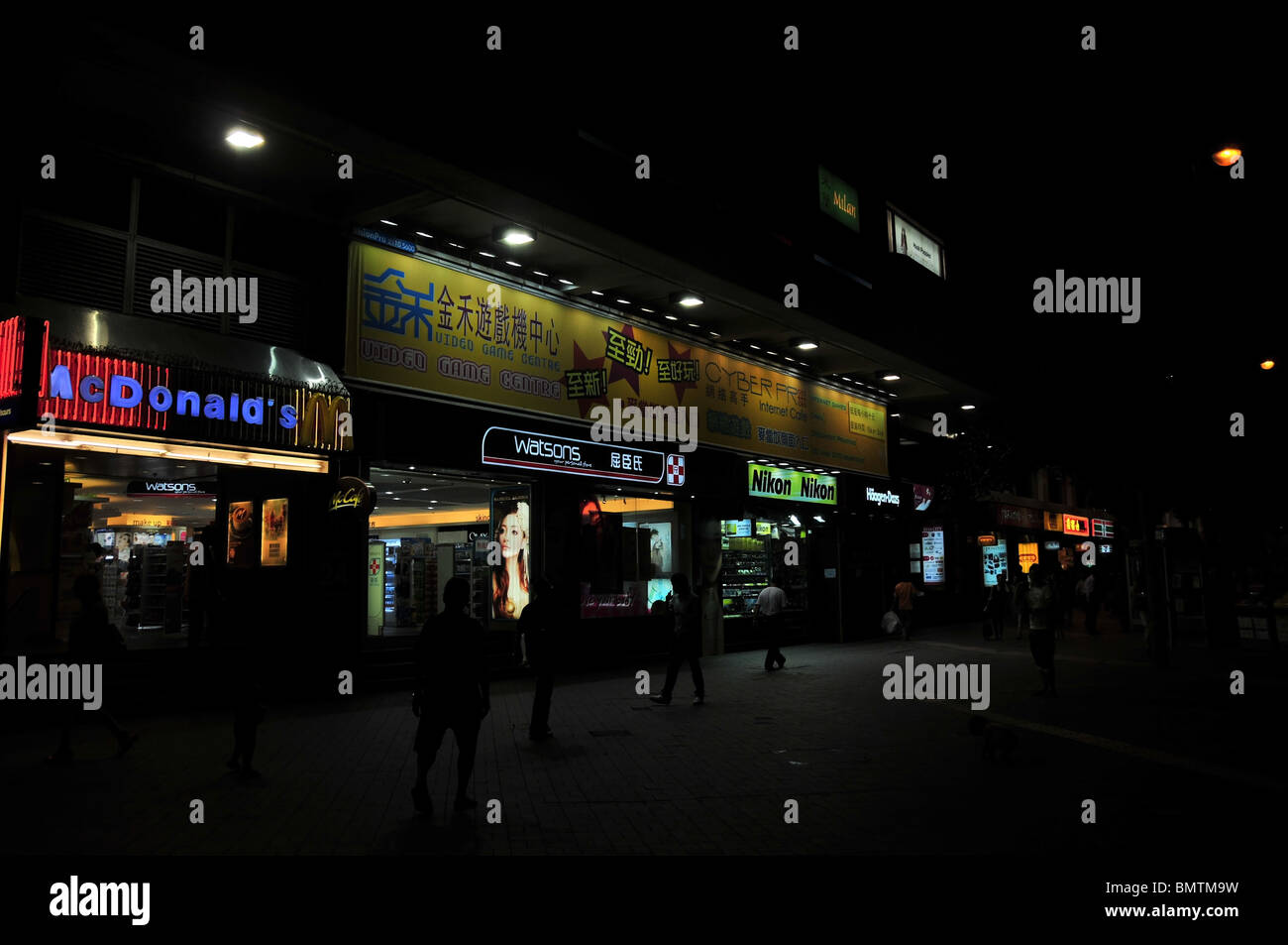 Black, night-time, neon shot of chain stores and shoppers, Tsim Sha ...
