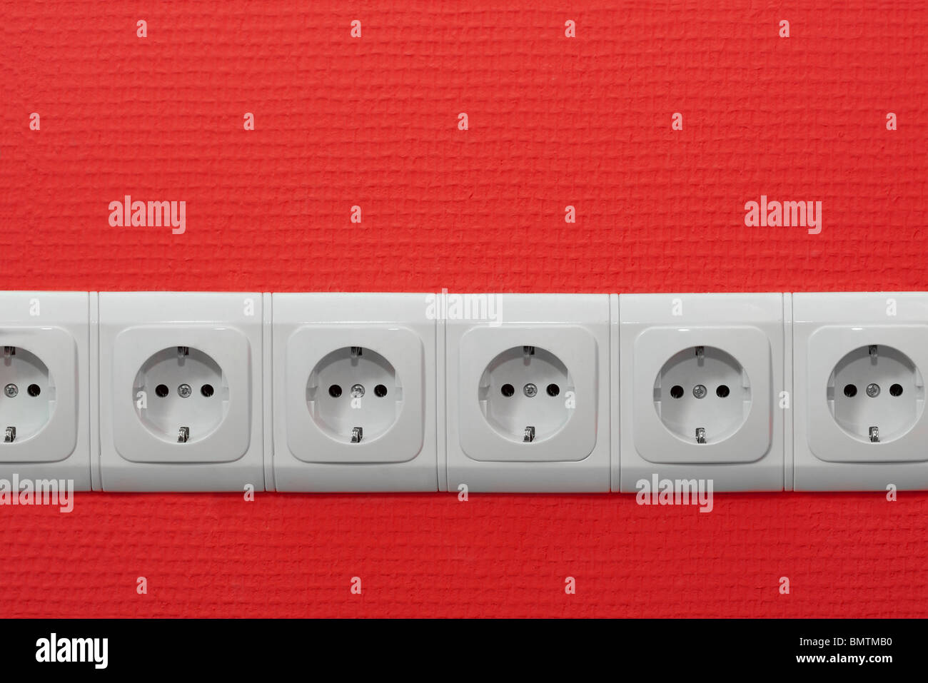 Endless row of electric outlets on red wall Stock Photo - Alamy