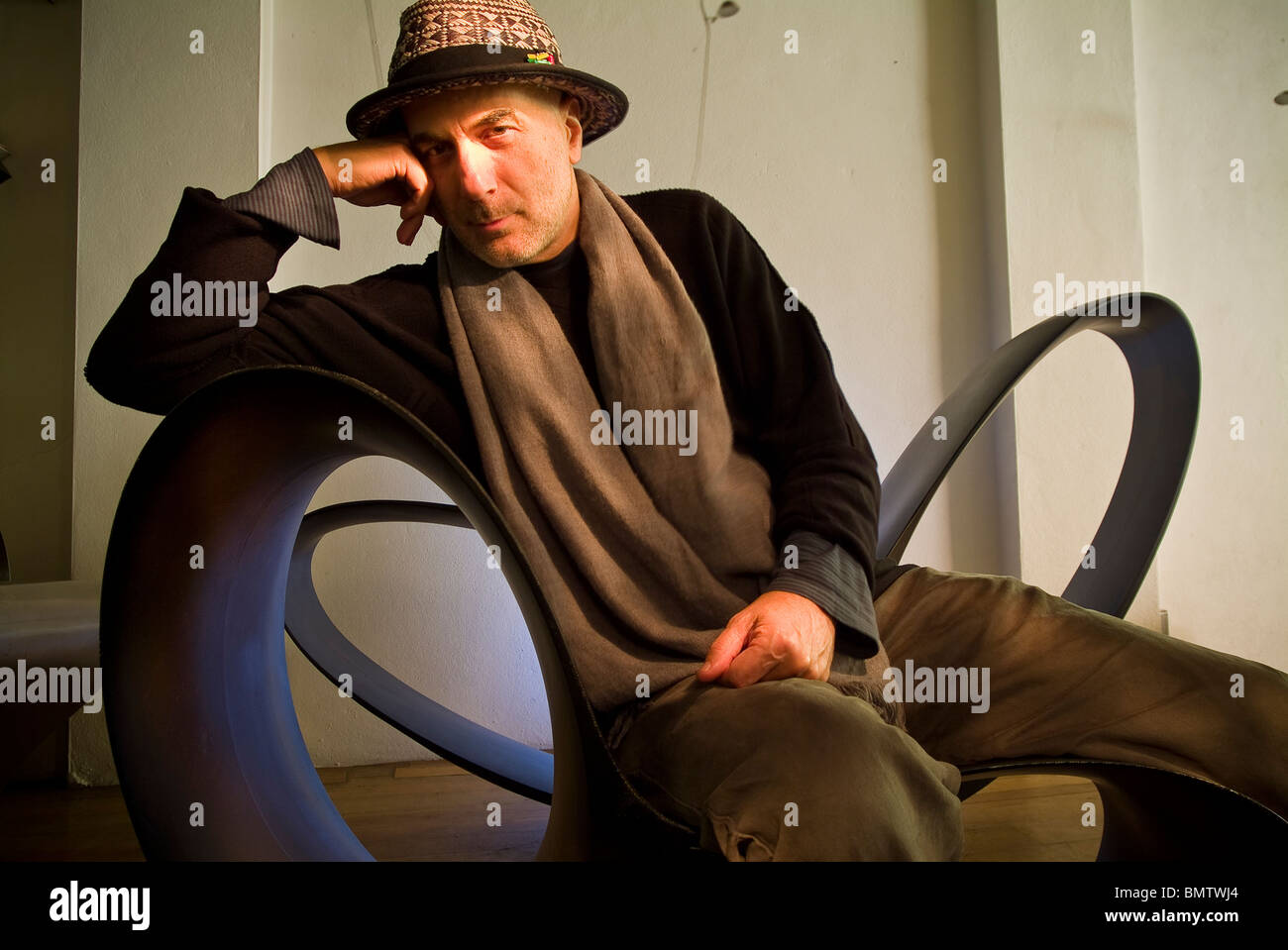 Designer Ron Arad sitting on one of his chairs in his studio in Camden ...