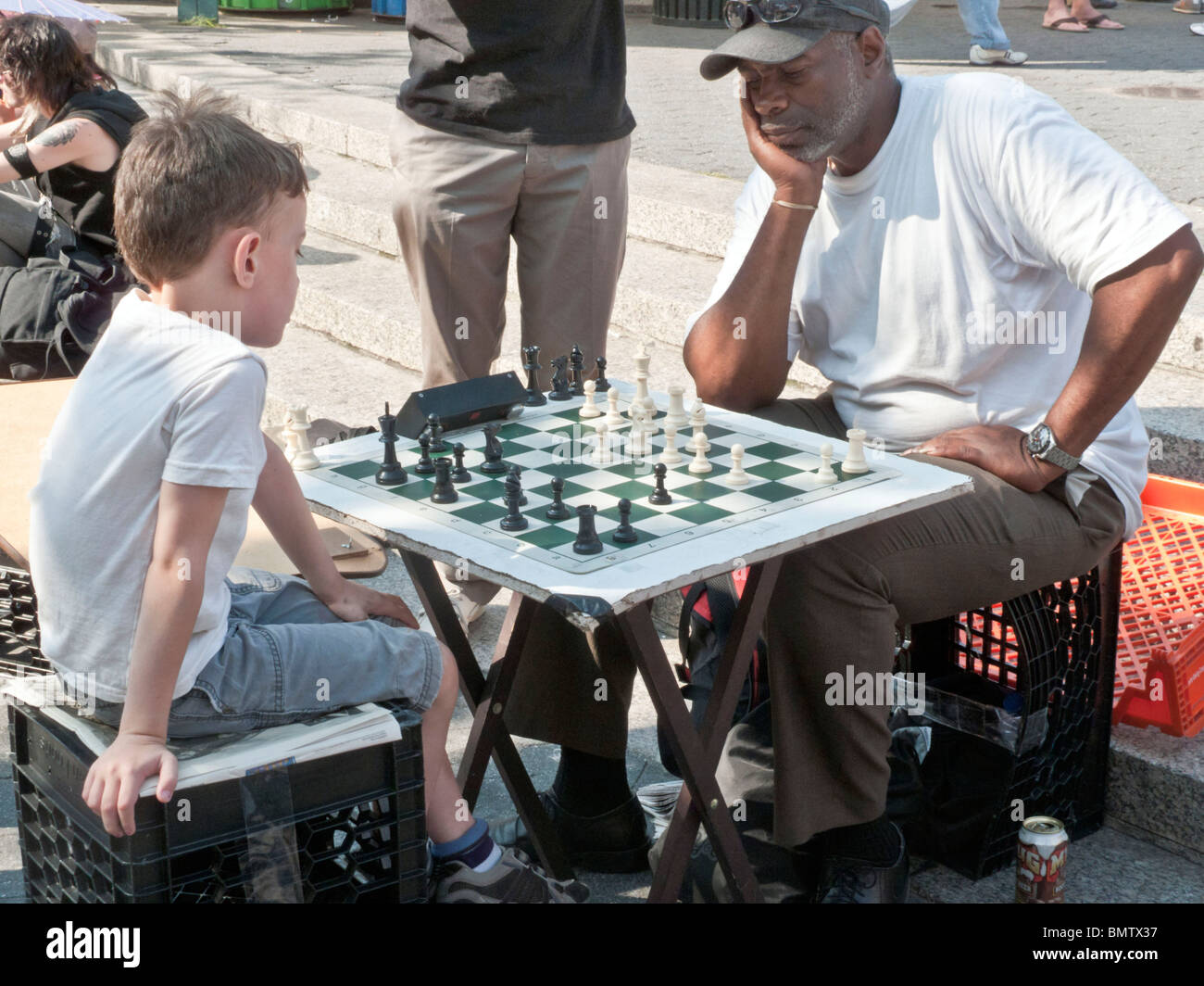 adult black man & small Caucasian boy sitting on overturned plastic ...