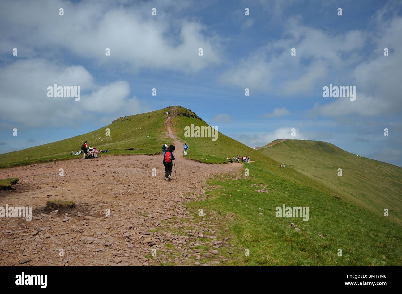 A walker strides out towards the summit of Corn Du with Pen y Fan in ...