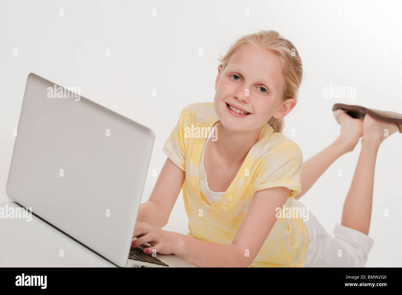 Child laying on a white background working on laptop computer Stock ...