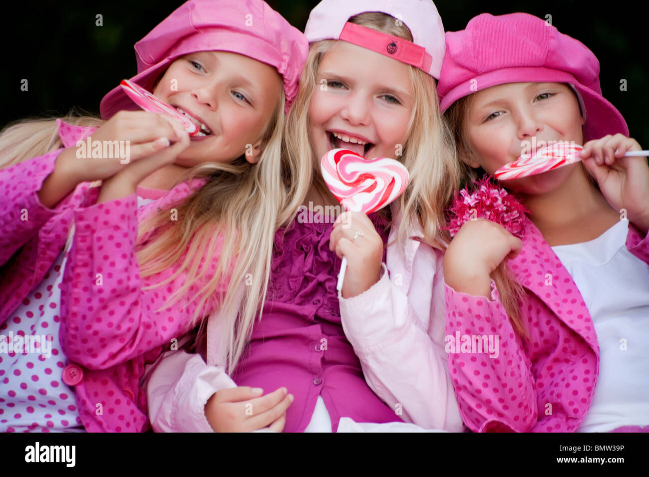 Happy children having pink clothes and a lollipop Stock Photo - Alamy