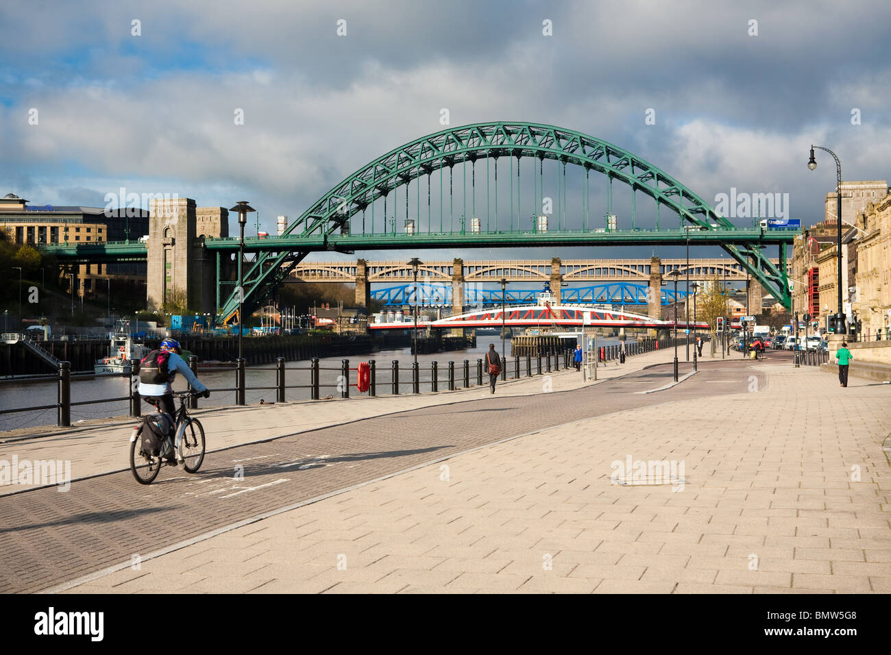 Cyclist riding alongside the River tyne with Tyne Bridge in the ...