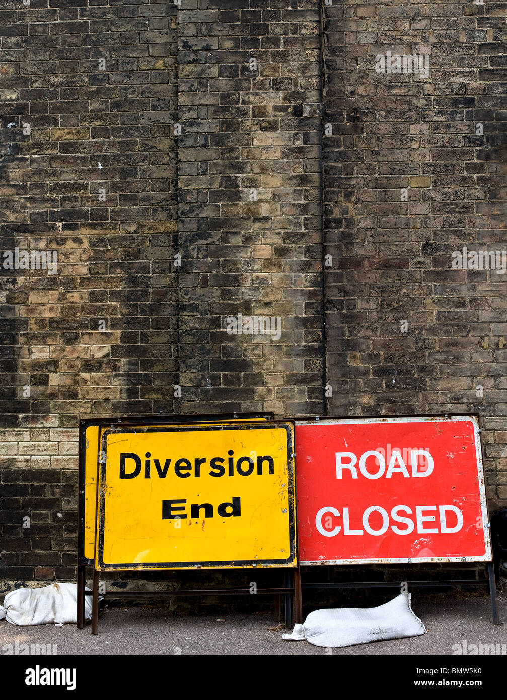 Traffic diversion signs leaning against a brick wall. Photo by Gordon ...