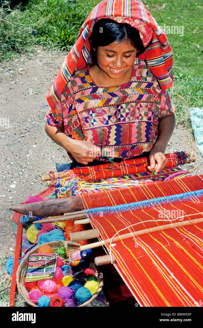 A young Mayan girl weaves colorful cloth with traditional patterns on ...
