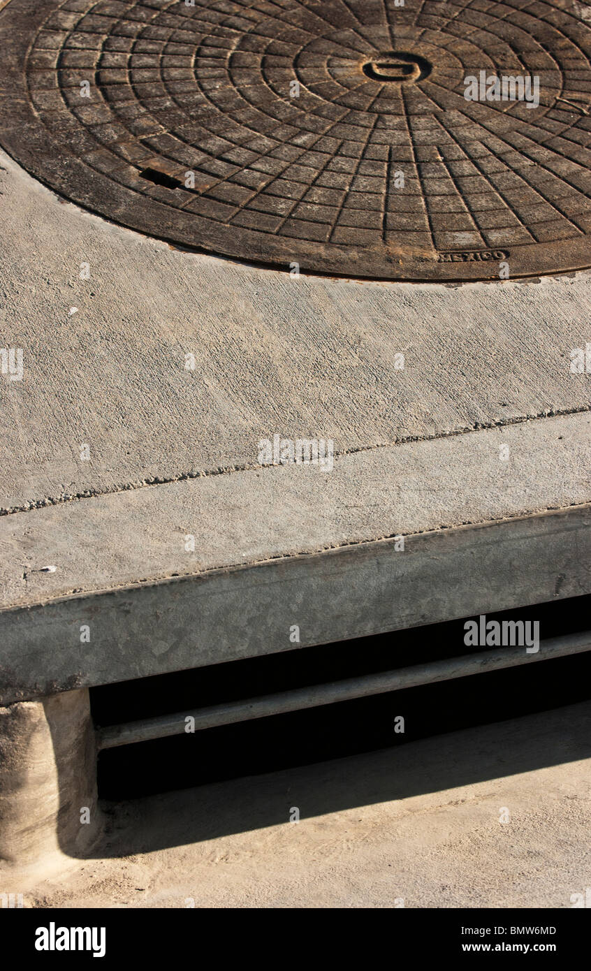 Curb drain with manhole cover Stock Photo - Alamy