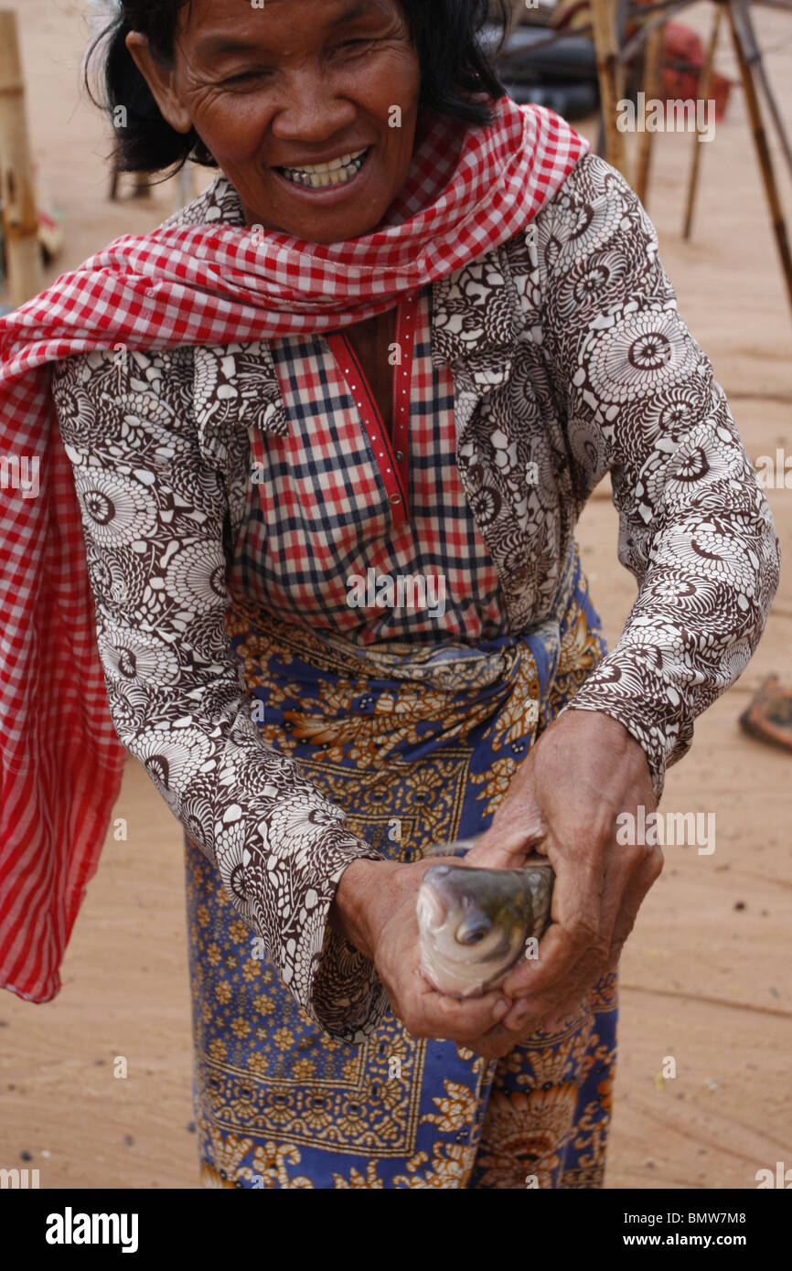 An old Khmer woman holds fish just caught in the Western Baray at ...