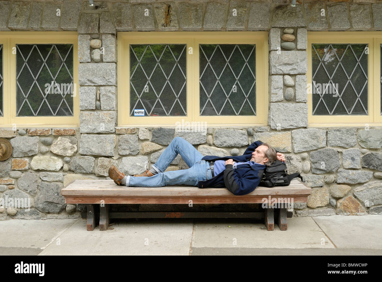 Man sitting laying on a wooden bench waiting Stock Photo - Alamy