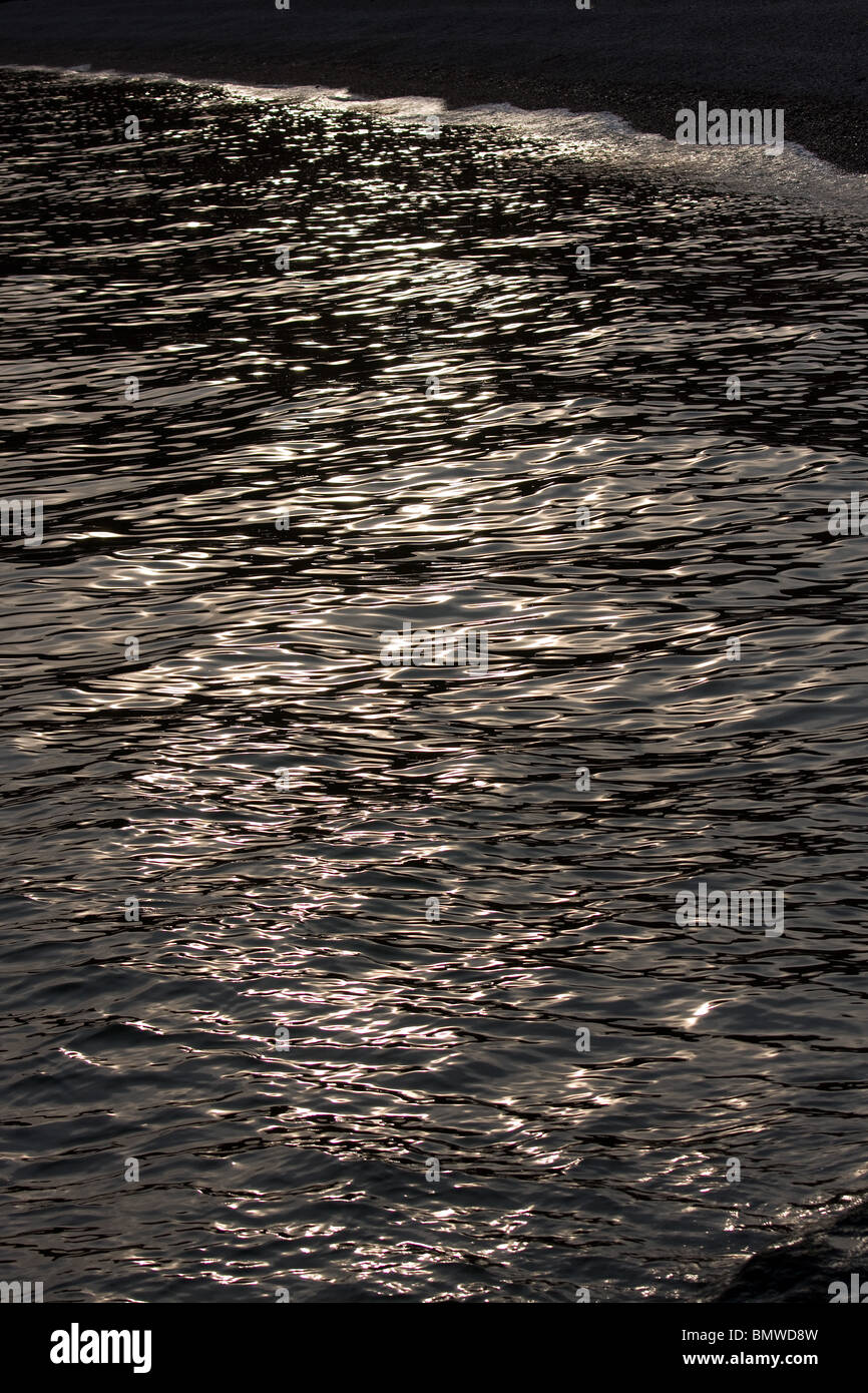 The last rays of sun reflected on the waves Stock Photo - Alamy