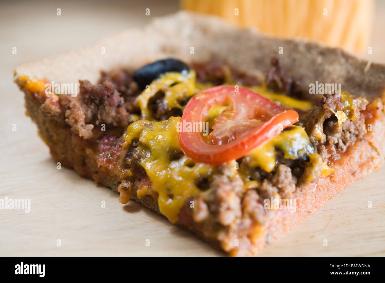 Cheeseburger pizza with wheat crust. Block of cheddar cheese in the ...