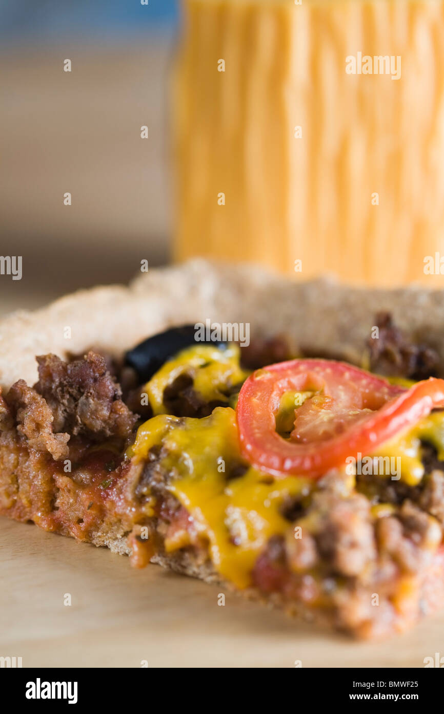 Cheeseburger pizza with wheat crust. Block of cheddar cheese in the ...