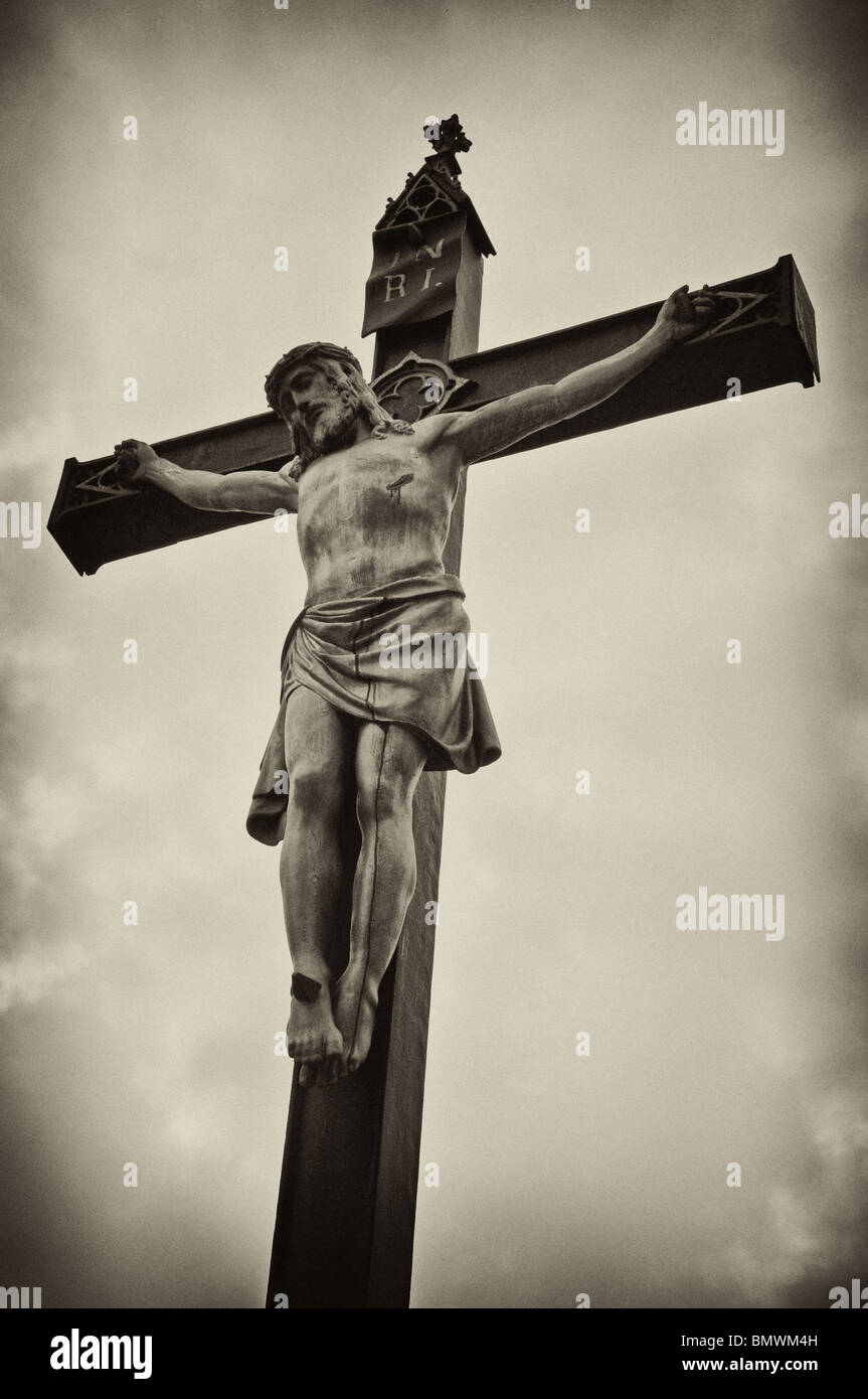 A statue of Jesus Christ crucified on a cross over a grunge background, black and white photo ...