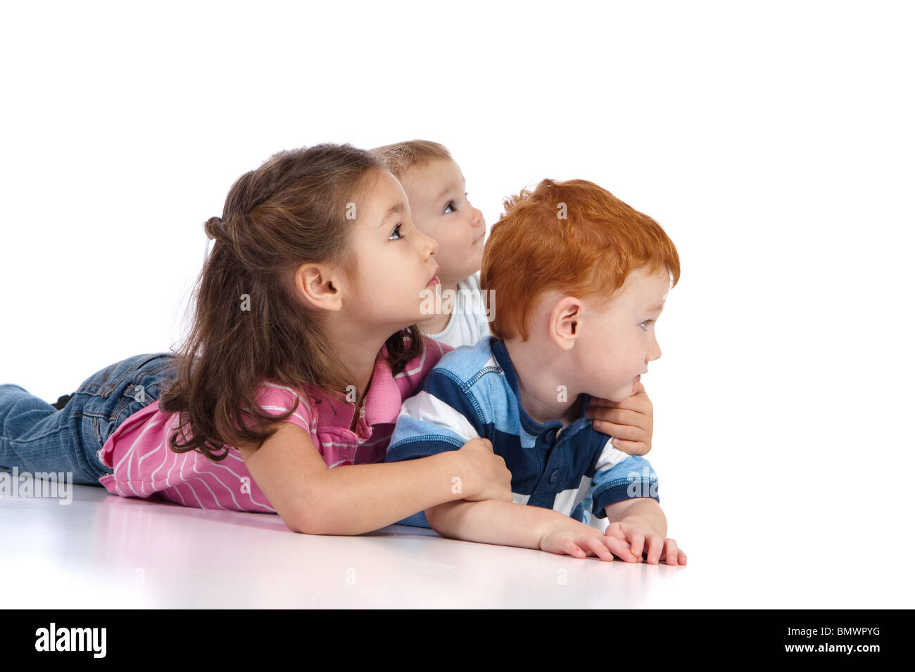 Three young kids watching something away from camera. Isolated ...