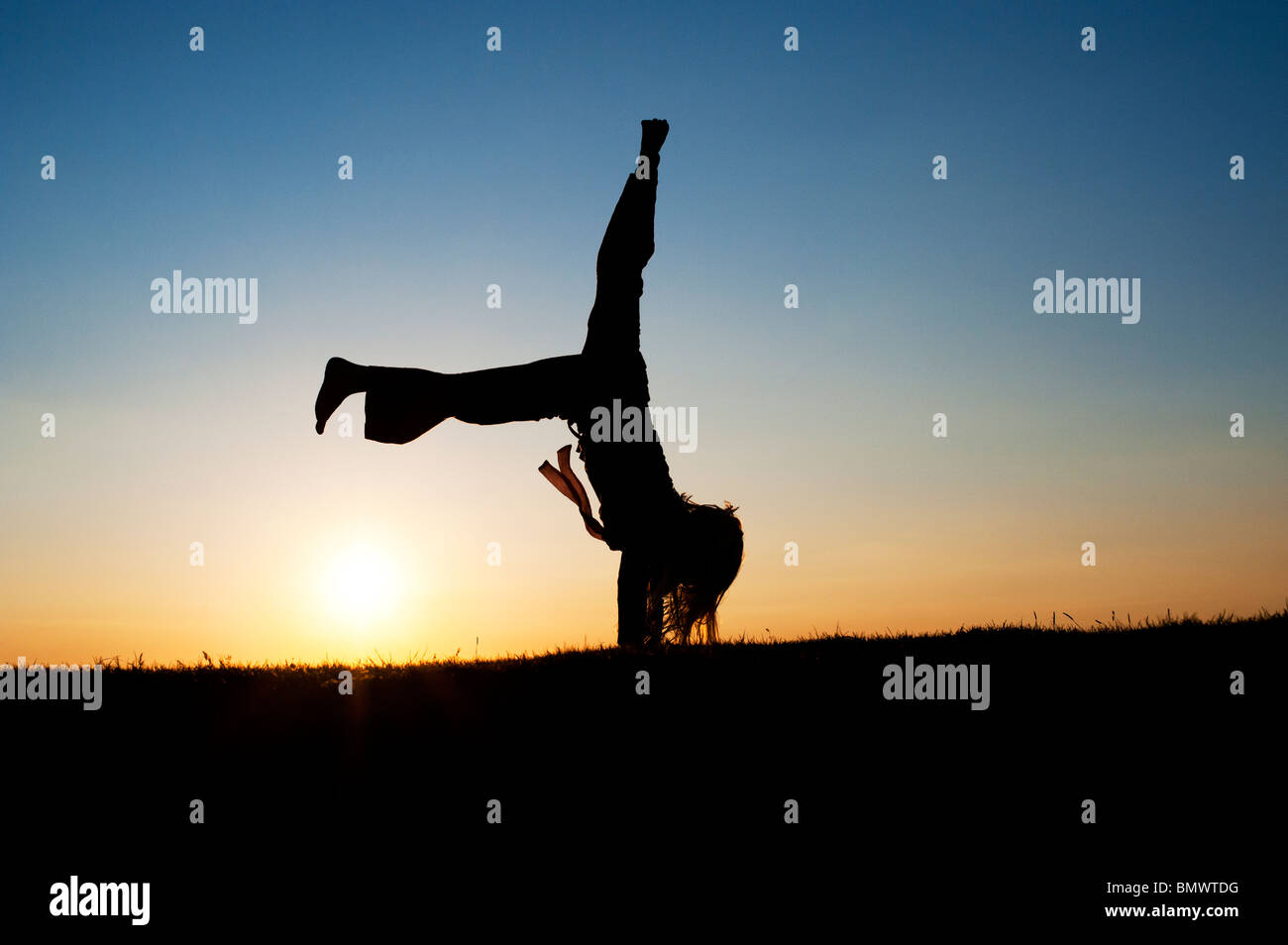 Young Girl energetically having fun doing a handstand at sunset ...