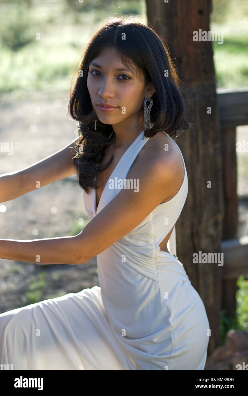 A young and very pretty mixed race woman is wearing a white formal ...