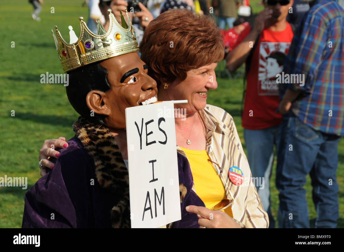 Female Tea Party protesters embraces a man wearing a Barrack Obama mask ...