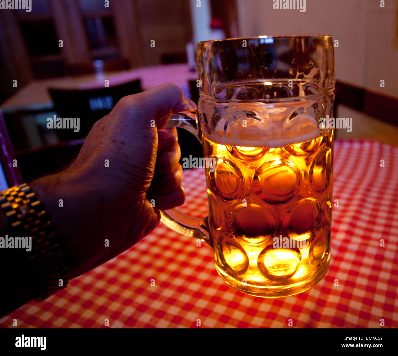 Close up of a liter glass of lager with a foamy head in a man's hand ...