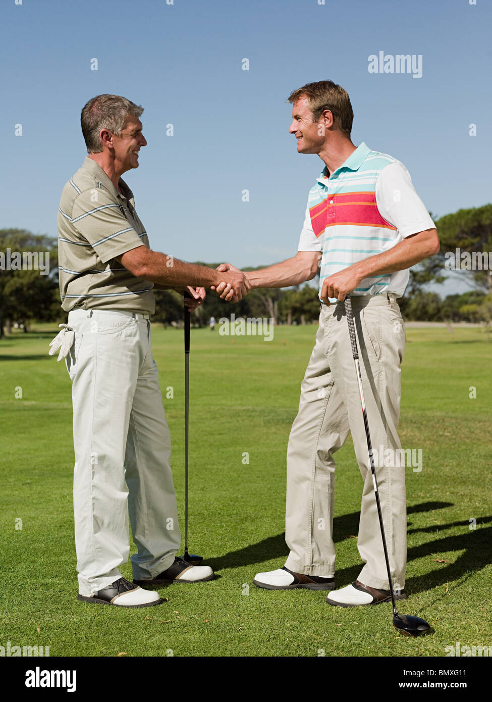 Two mature men shaking hands on golf course Stock Photo - Alamy