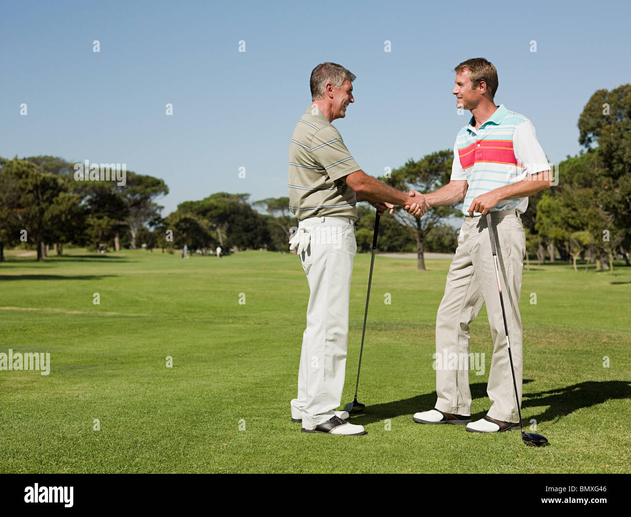 Two mature men shaking hands on golf course Stock Photo - Alamy
