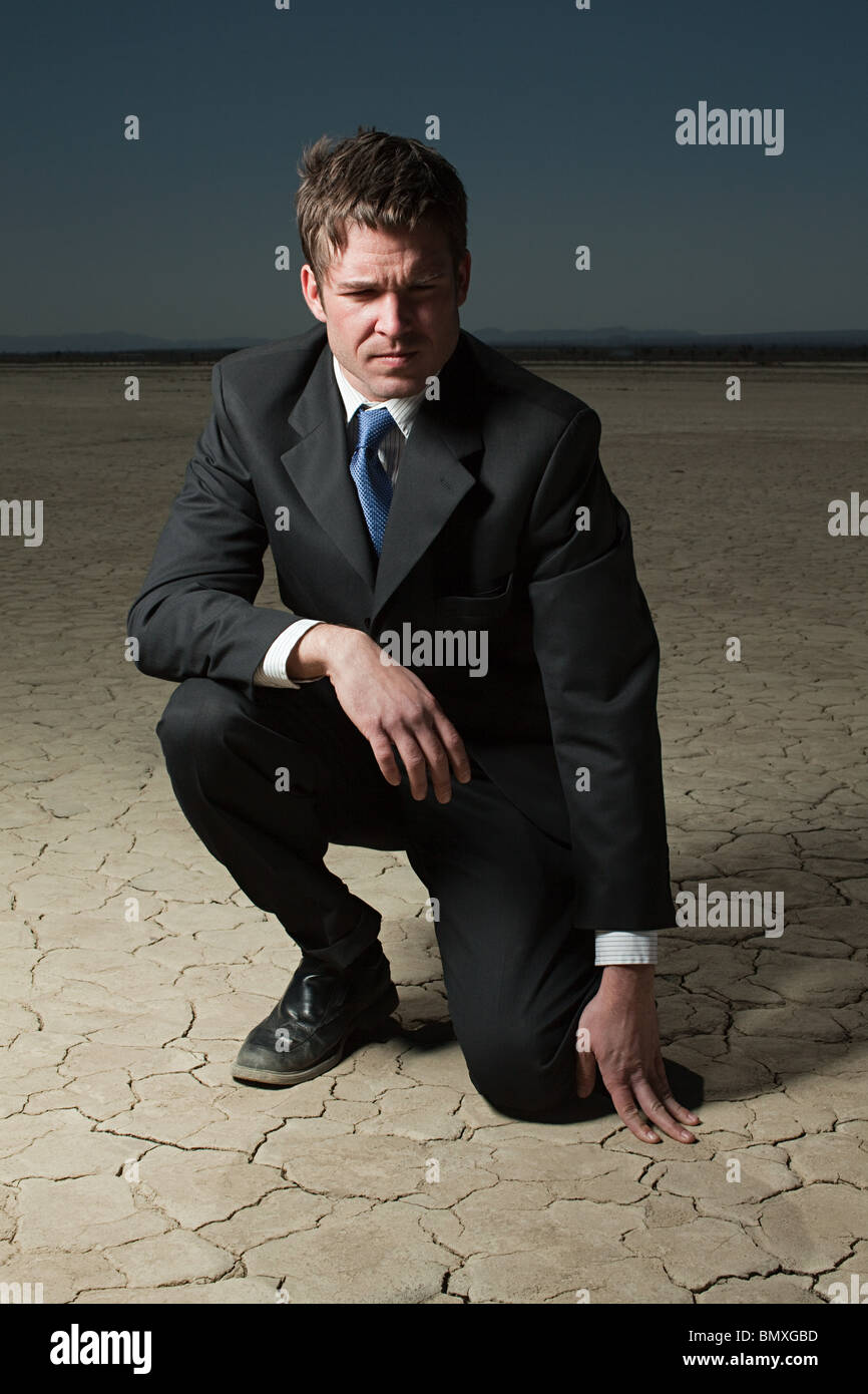 Businessman crouching in desert landscape Stock Photo - Alamy