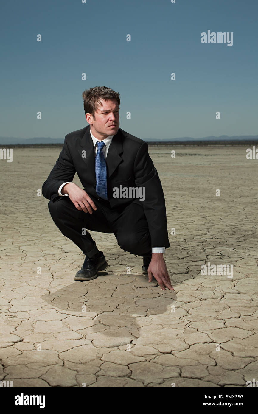 Businessman crouching in desert landscape Stock Photo - Alamy