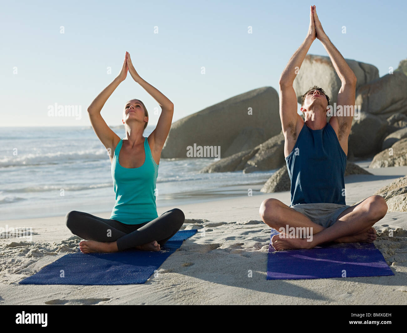 Young couple doing yoga on beach Stock Photo - Alamy