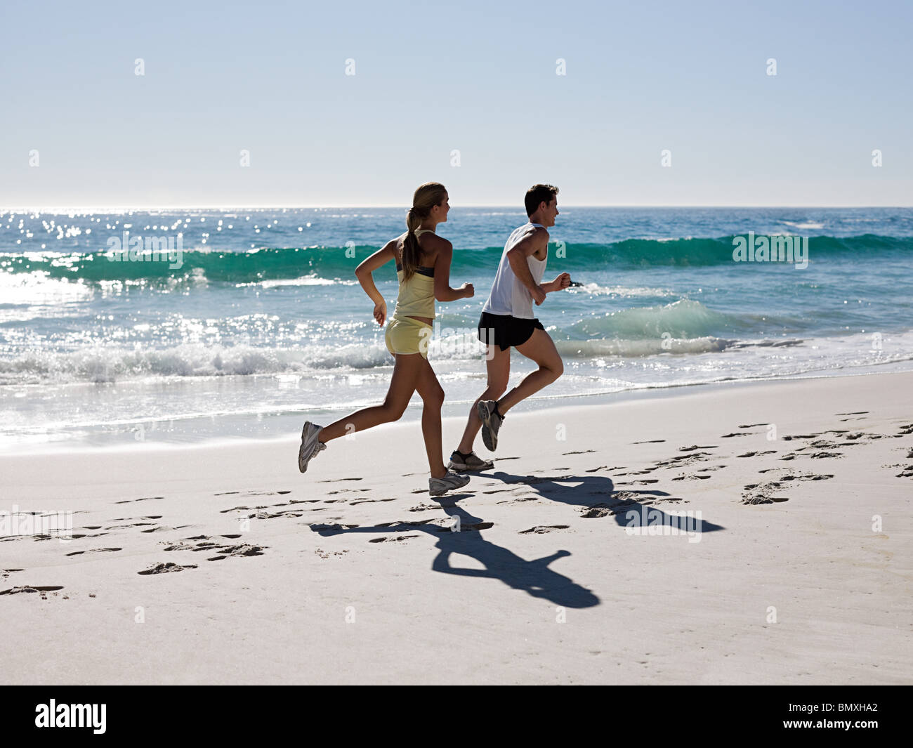 Young couple jogging on beach Stock Photo - Alamy