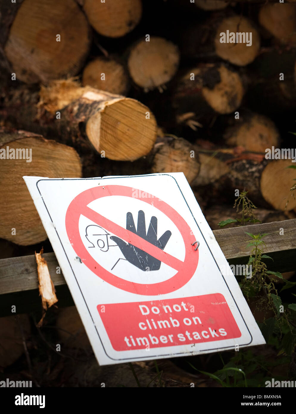 Cut wooden logs stacked ready for drying displaying a warning sign ...