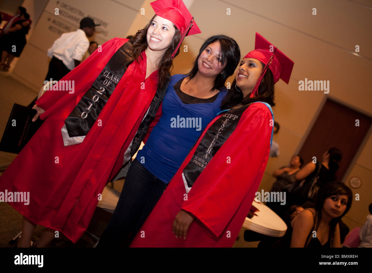 Hispanic female graduates pose with guest after graduation ceremony for ...