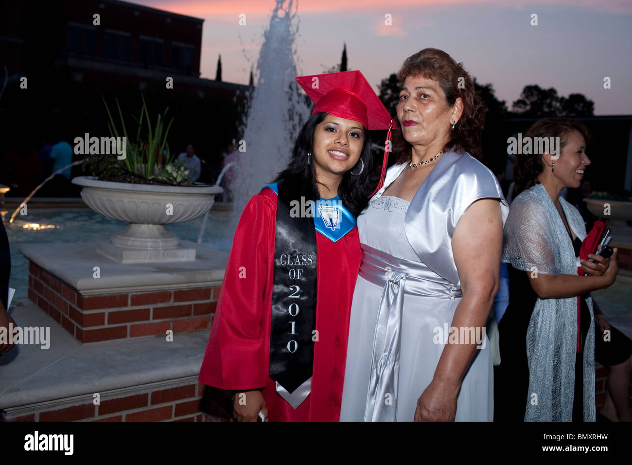 Hispanic female graduate poses with a guest after graduation ceremony ...