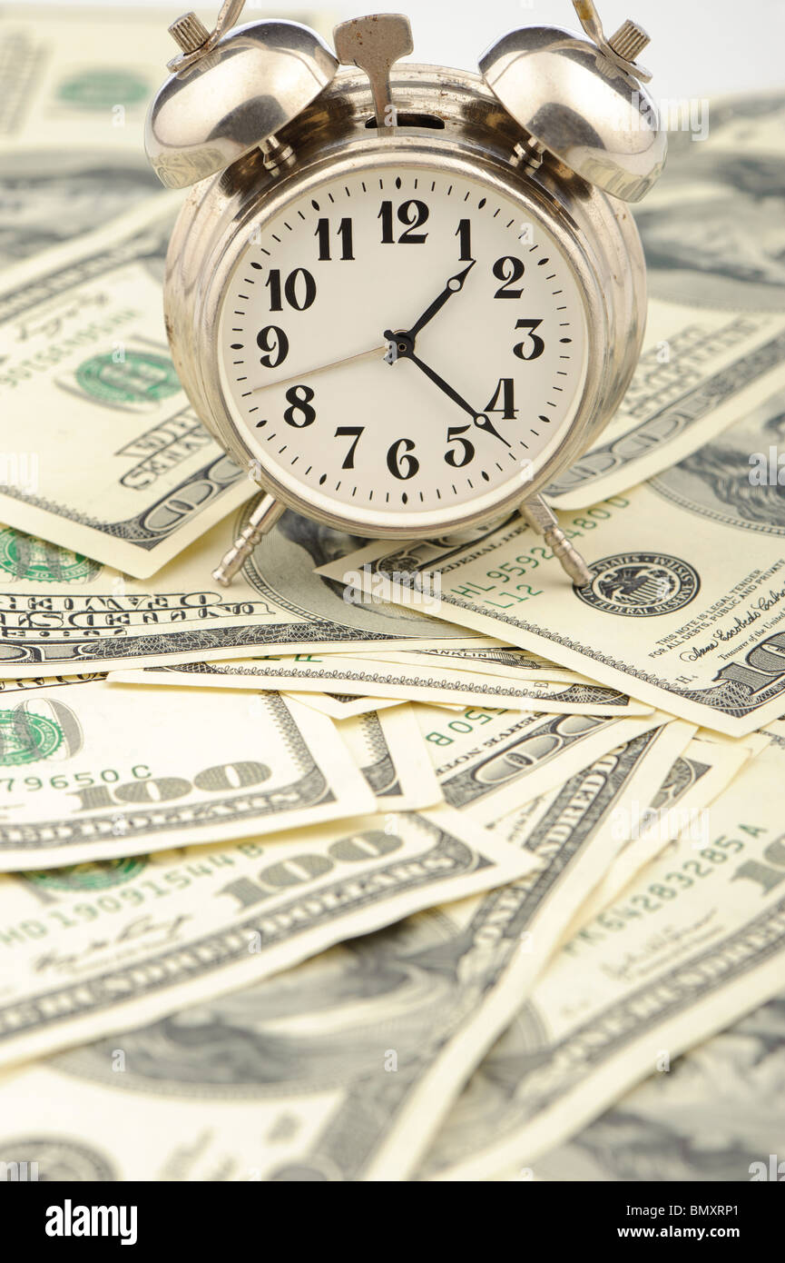 Time - money. Business concept. Analog hours on a heap of paper dollars ...