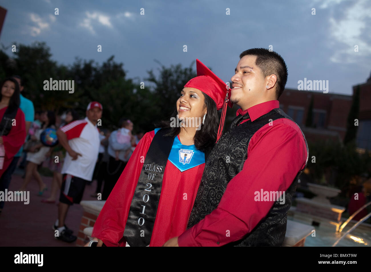 Hispanic female graduate poses with guest after graduation ceremony for ...