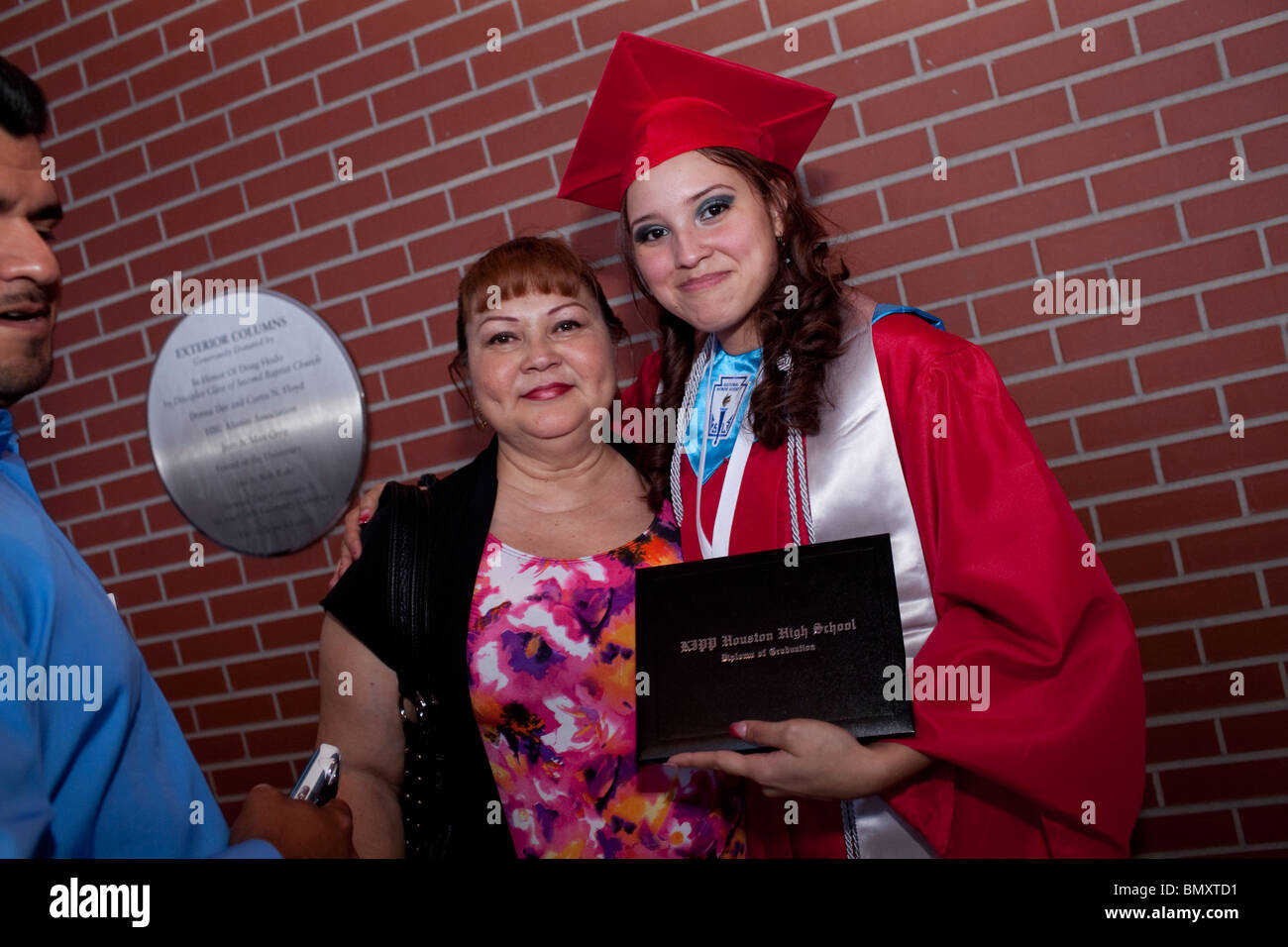 Anglo female graduate poses with a guest after graduation ceremony for ...